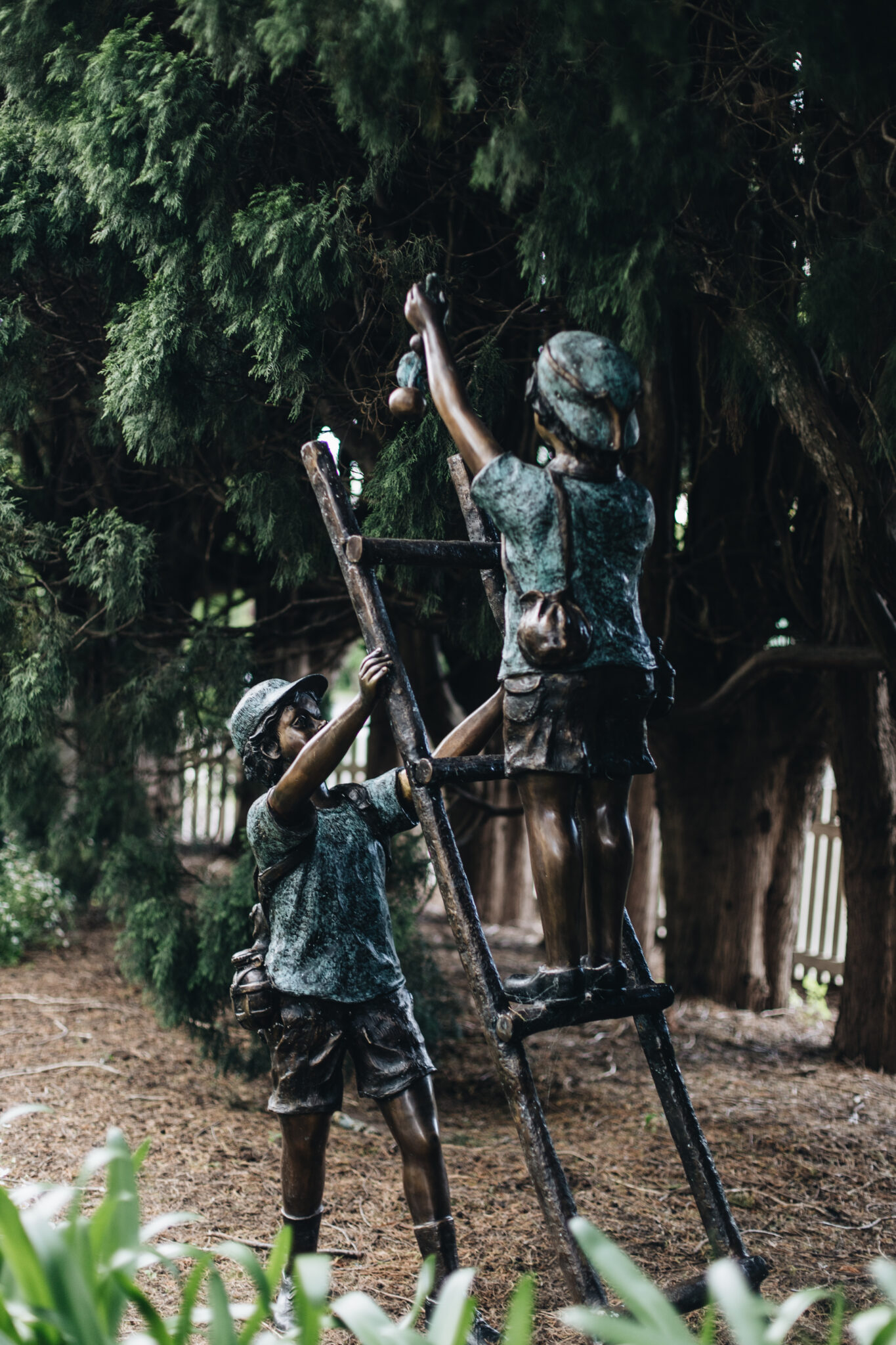 A bronze statue of two boys climbing a ladder - The Old Pot Factory